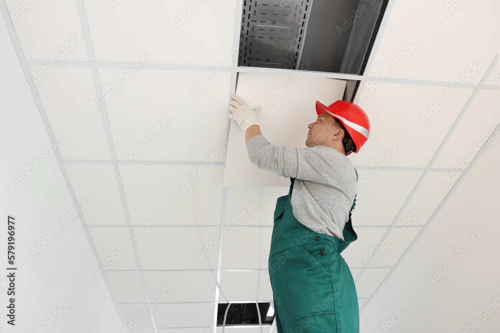 Suspended ceiling installation. Builder working with PVC tile Stock ...