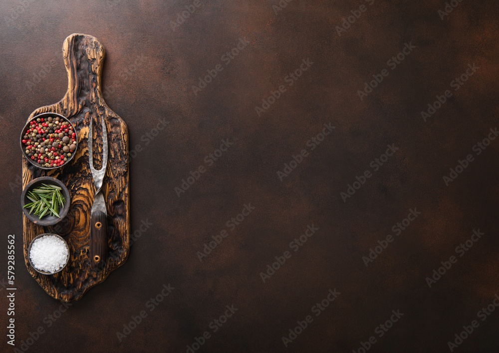 Chopping board with salt,pepper and rosemary with barbeque steel fork ...