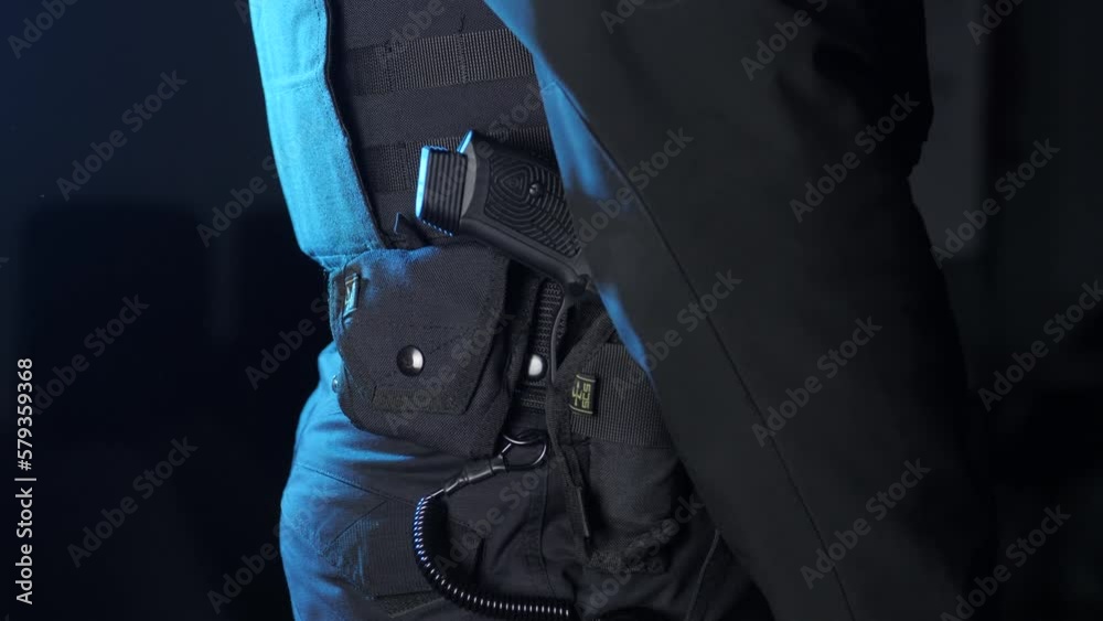 Crime scene. Human inserts a pistol into a holster and pulls it out of ...
