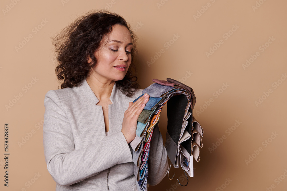Multi-ethnic woman in casual clothes, touches fabric samples for sofa ...