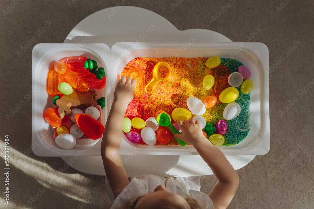 Fotografia do Stock: Child playing with colored rice and Easter eggs in ...