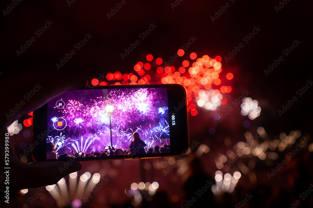 People take pictures of fireworks on a smartphone. Concert with the ...