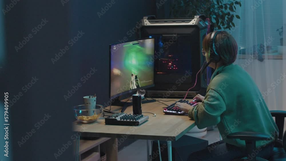 Medium shot of young Chinese woman sitting in front of computer at home ...