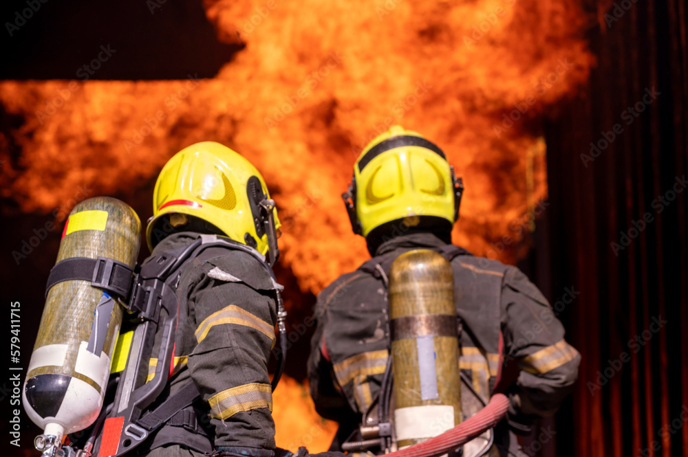 firefighters wearing fire fighter suit for safety and using twirl water ...