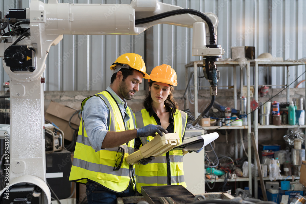 Plakat Male and female technician control robot arm system welding with ... Plakat Male and female technician control robot arm system welding with ...