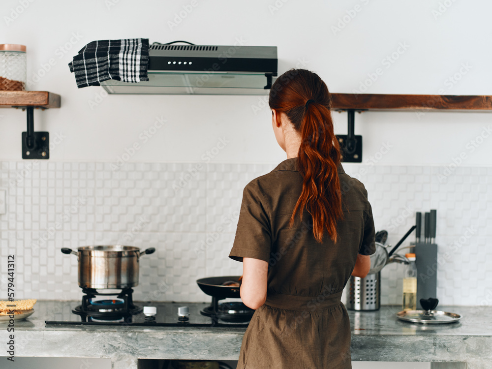 A woman at home smile in the kitchen prepares food stands with her back ...