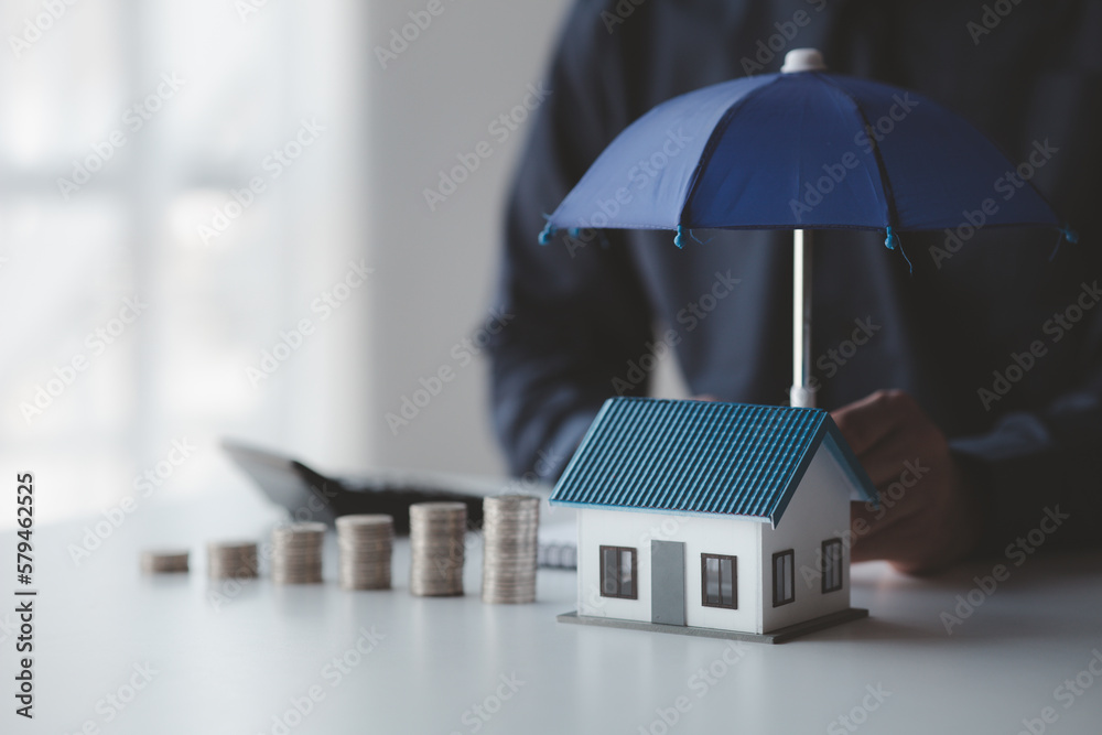 Individuals holding small umbrellas and model homes, housing insurance ...