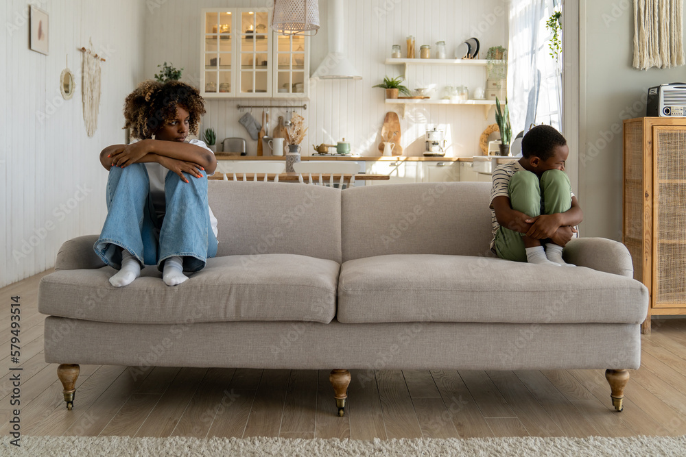 Foto de Offended African American mother and child boy sit on opposite ...