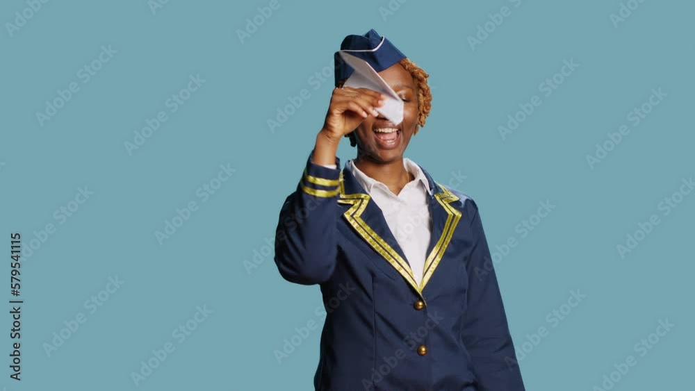 Cheerful silly stewardess playing with paper plane, having fun with ...
