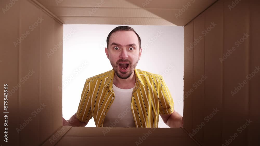 Long-awaited gift. Excited man in yellow shirt unpacking, emotionally ...