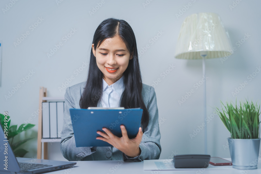 Young Asia business woman working with annual summary report and laptop ...