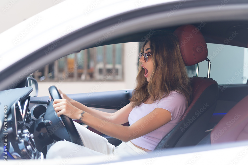 Beautiful young happy smiling woman driving her expensive luxury car ...