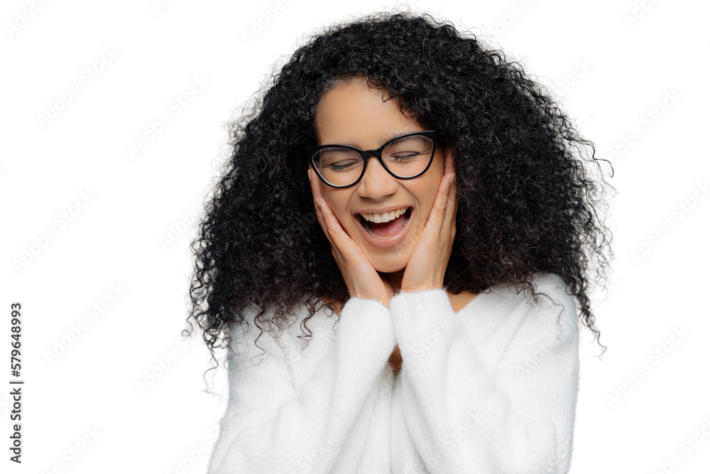 Overemotive female touches cheeks laughs from joy, keeps eyes closed ...