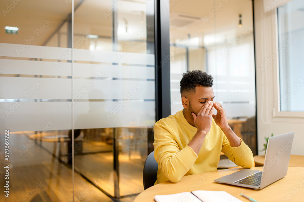 Overworked from work frustrated indian guy sitting at the desk, looking ...