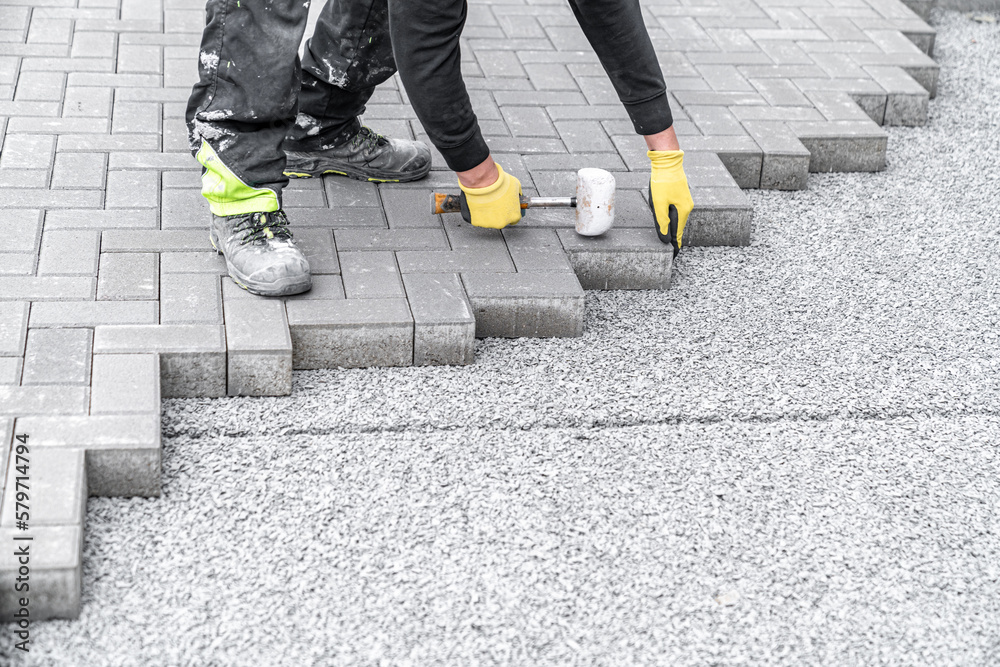 laying interlocking pavers during the construction of sidewalks and ...
