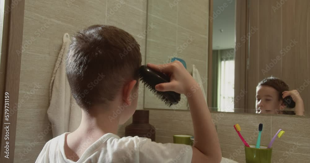 Stockvideon Caucasian child combing his hair with a comb, looking in ...