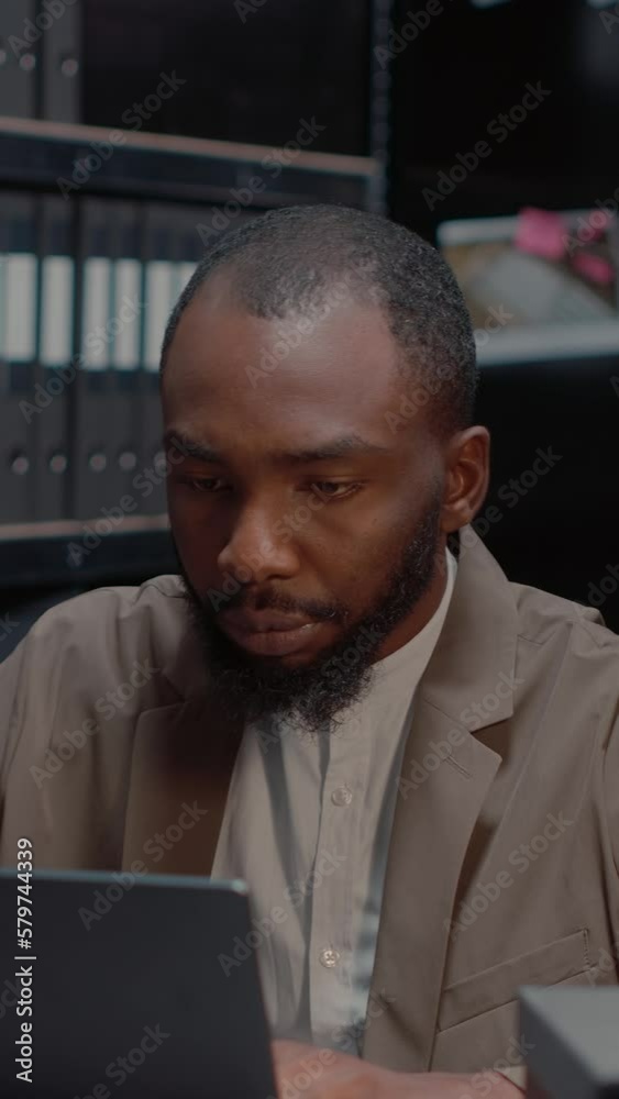 Vertical video: African american law agent studying crime scene photos ...
