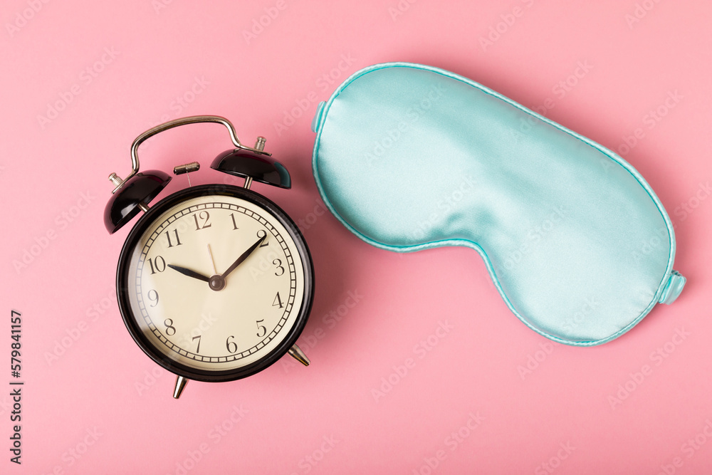 Sleep mask and alarm clock on a pink background.LET'S RAISE. The ...