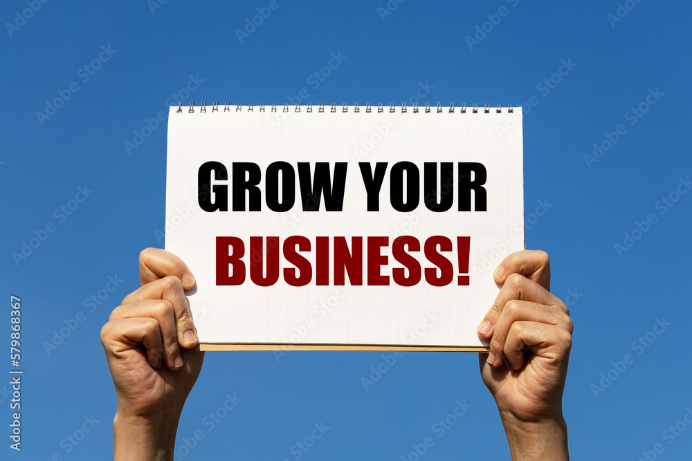 Grow your business text on notebook paper held by 2 hands with isolated ...