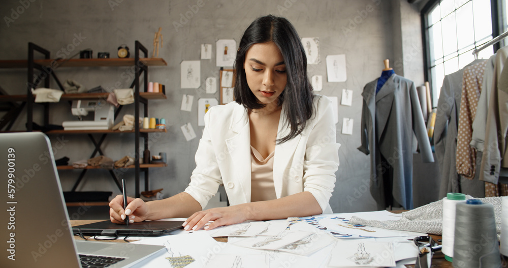 Asian female clothing designer is drawing her sketches on graphics ...