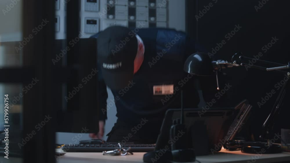 Security officer comes on workplace, sits by table and leans on back of ...