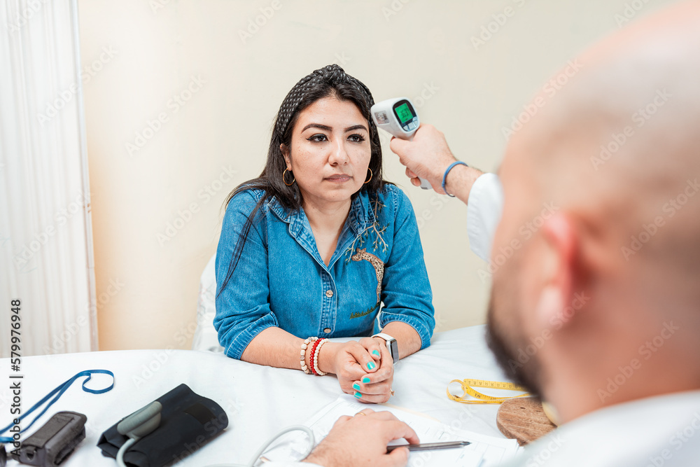 Doctor taking temperature to woman patient in office. Male doctor ...