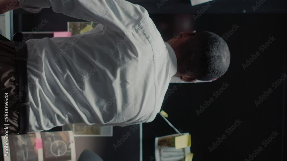 Vertical video: Professional police officer hanging clues on wall map ...