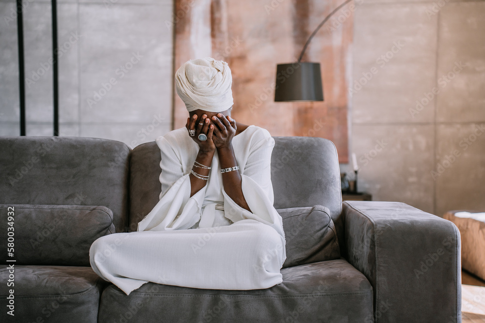 Unhappy African woman in white turban and white clothes crying, covers ...