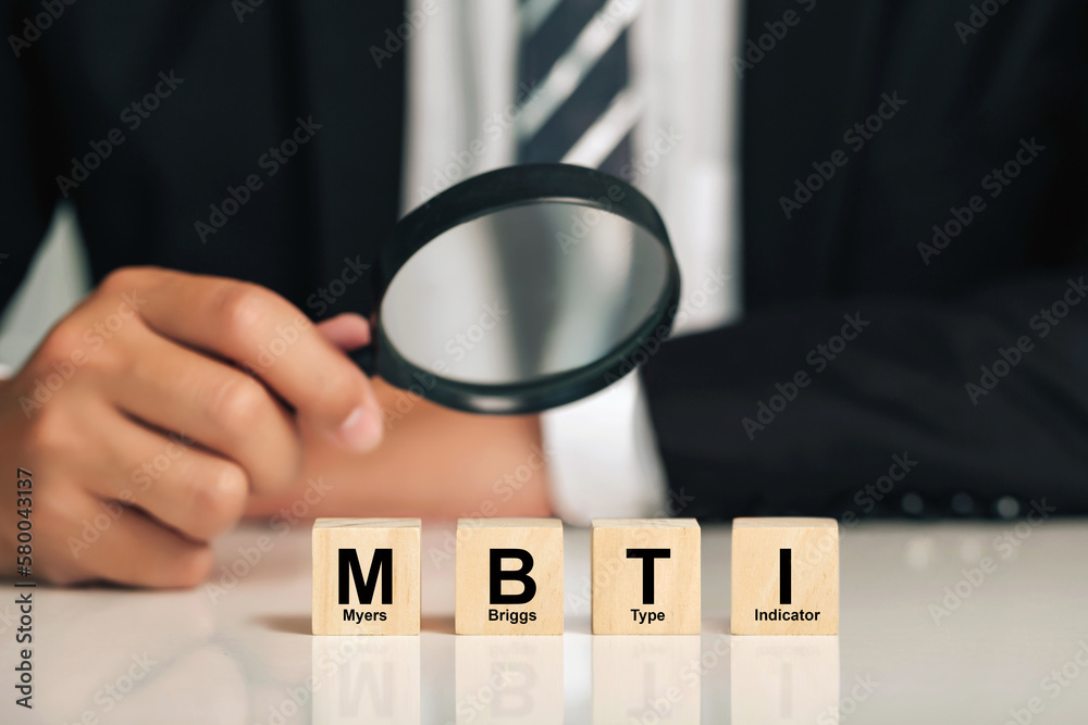 businessman holding magnifying glass with wooden cubes with MBTI ...