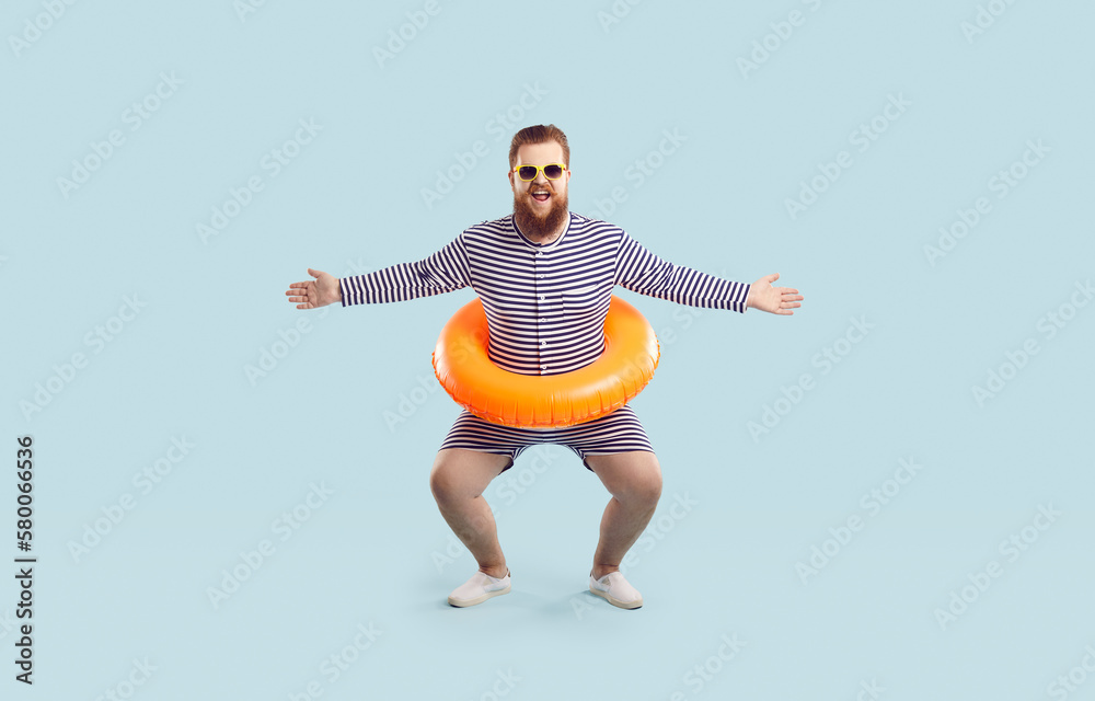 Funny fat man in retro swimsuit and sunglasses poses with swim tube ...