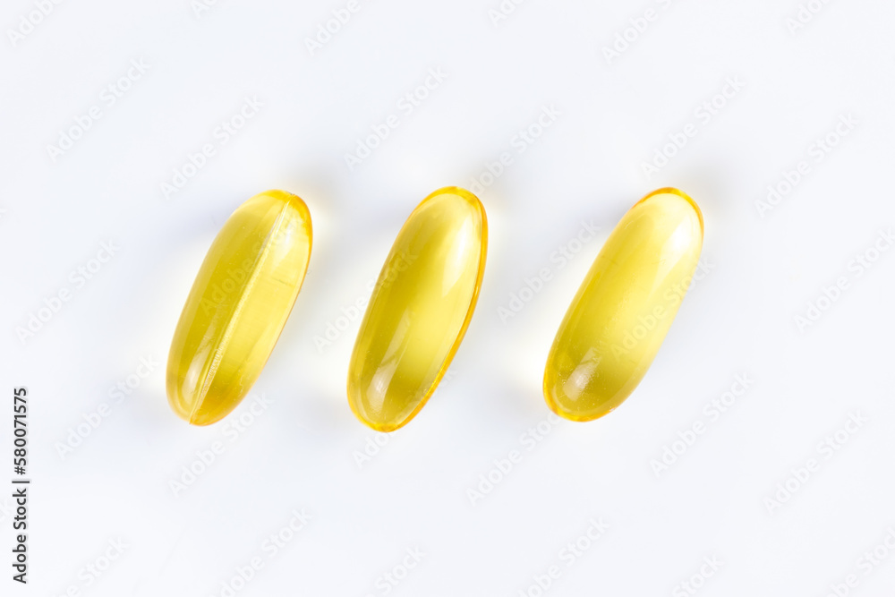 Three yellow transparent capsules with liquid Omega 3 on a white ...