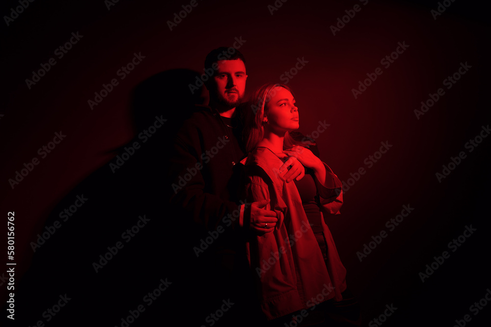 Young man standing behind woman and embracing gently in darkness with ...