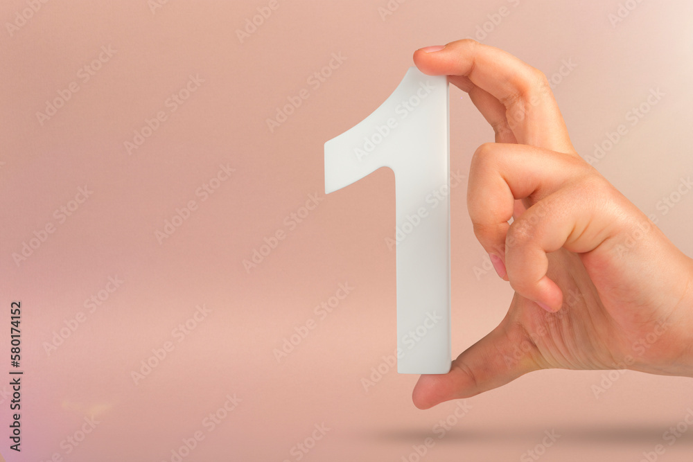 Number one in hand. A hand holds a white number one on a red background ...