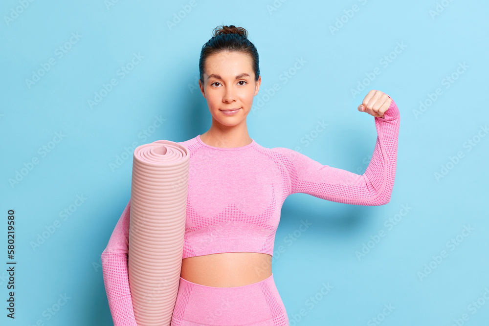 Powerful strong European woman raises arm shows biceps holds fitness ...