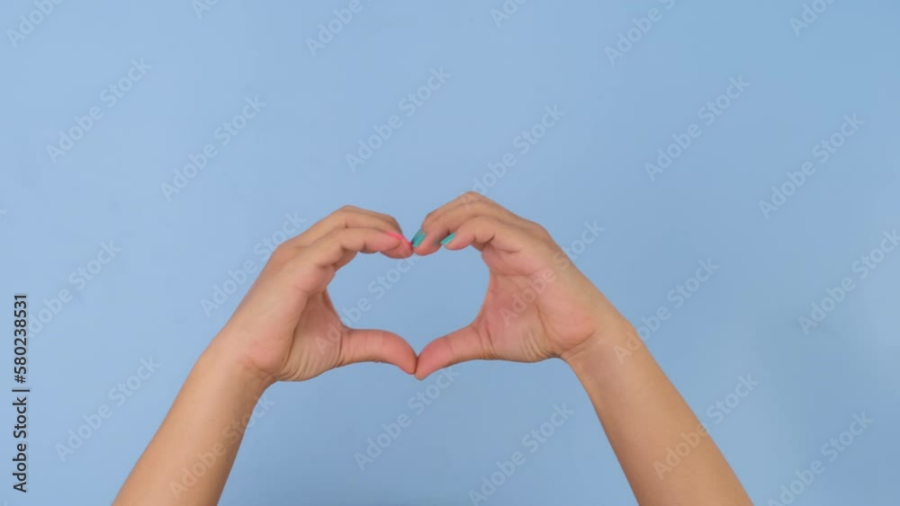 Female hand showing heart shape, love and sympathy symbol on pastel ...