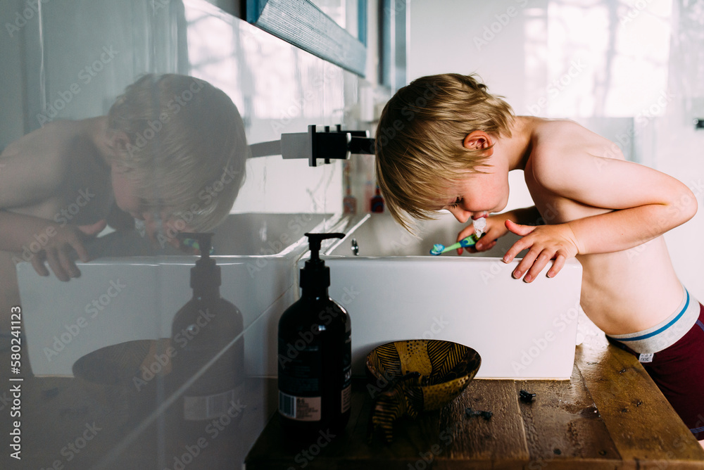 Side view of shirtless boy spitting while brushing teeth Stock Photo | Adobe Stock