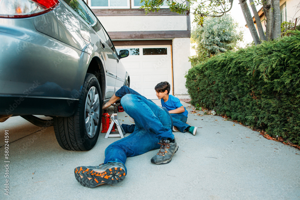 Father teaching son to repair car while lying down at driveway Stock ...