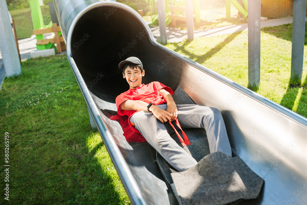 Child slides down metal chute in an adventure amusement park. Stock ...