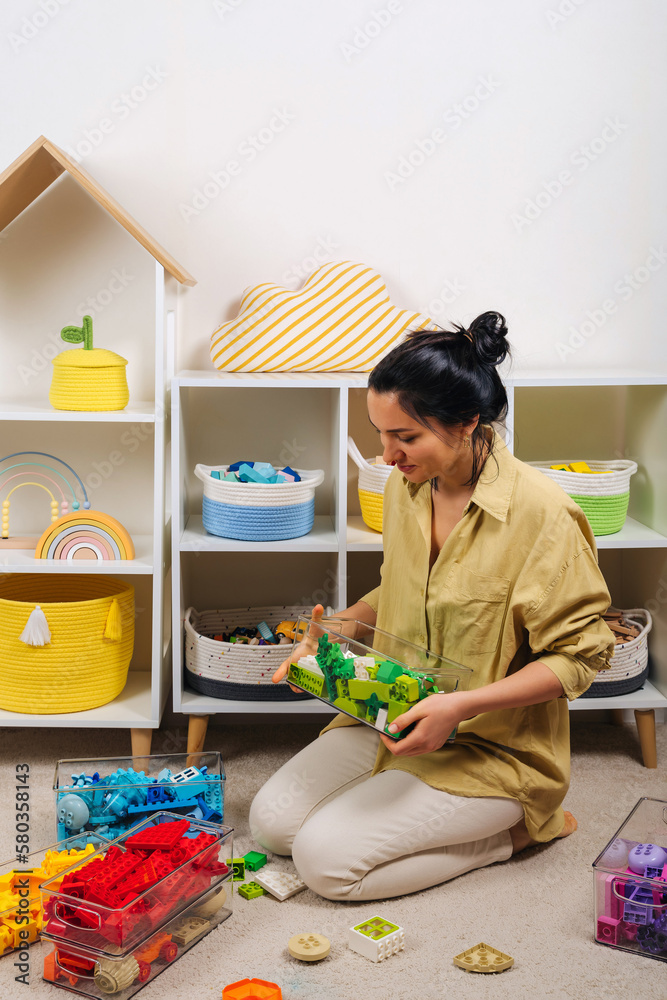 Mom sorted by colors and puts children's toys in transparent boxes and ...