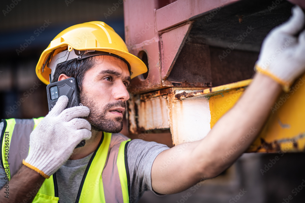 Caucasian warehouse worker in uniform with hard hat using mobile phone ...