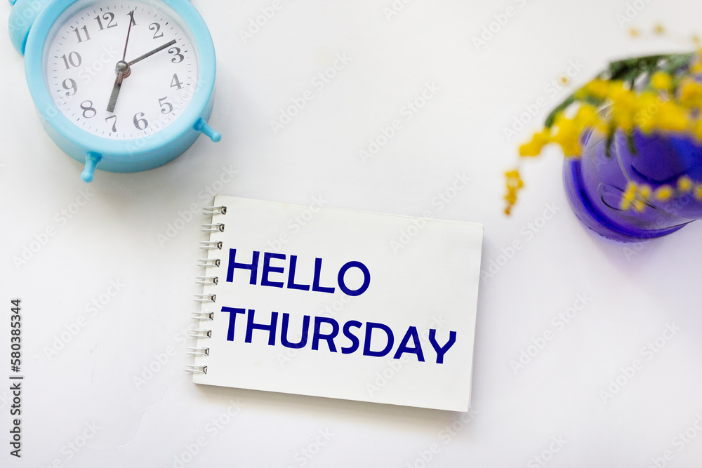Hello Thursday words on a notepad and a bouquet of mimosa flowers in a ...
