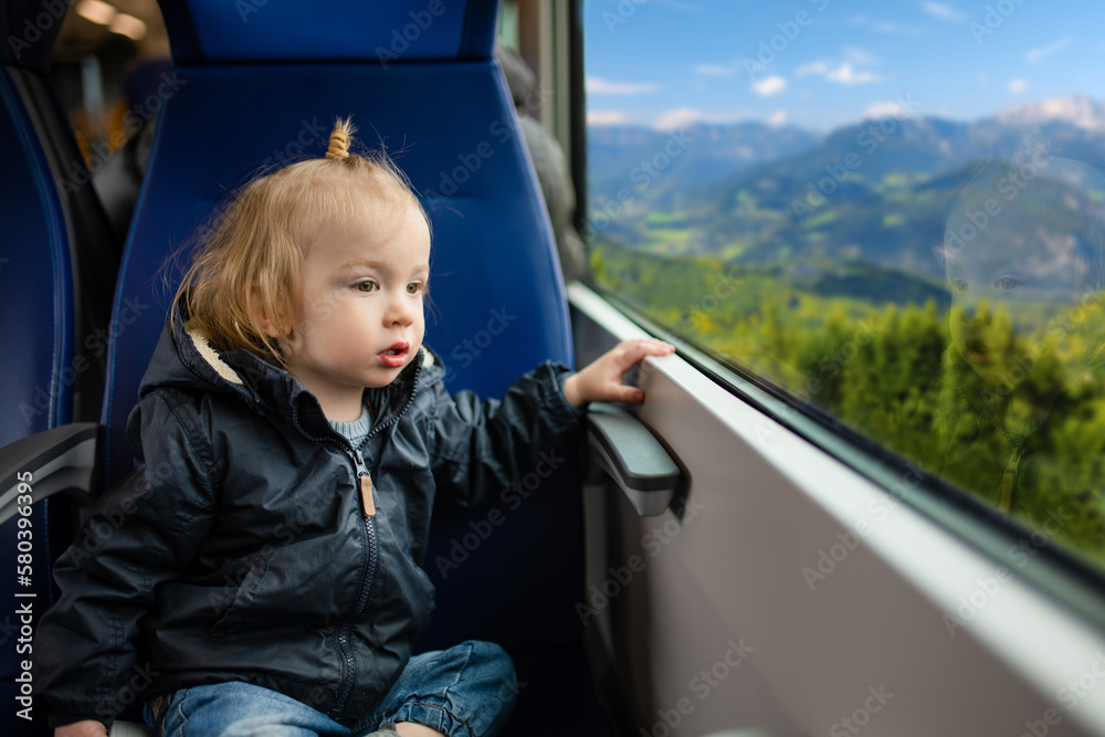 Toddler boy traveling by train. Little child sitting by the window in ...