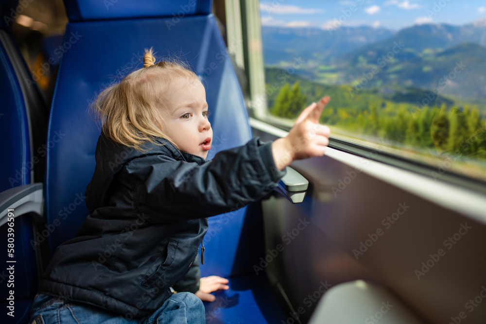 Toddler boy traveling by train. Little child sitting by the window in ...