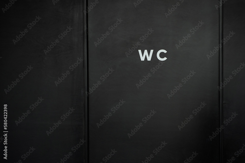 Black restroom door with a WC sign on it. Modern public toilet entrance ...