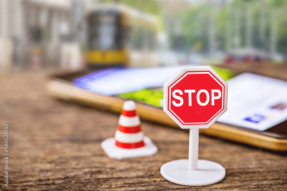 stop sign with traffic cone over blurred smart phone on wooden floor ...