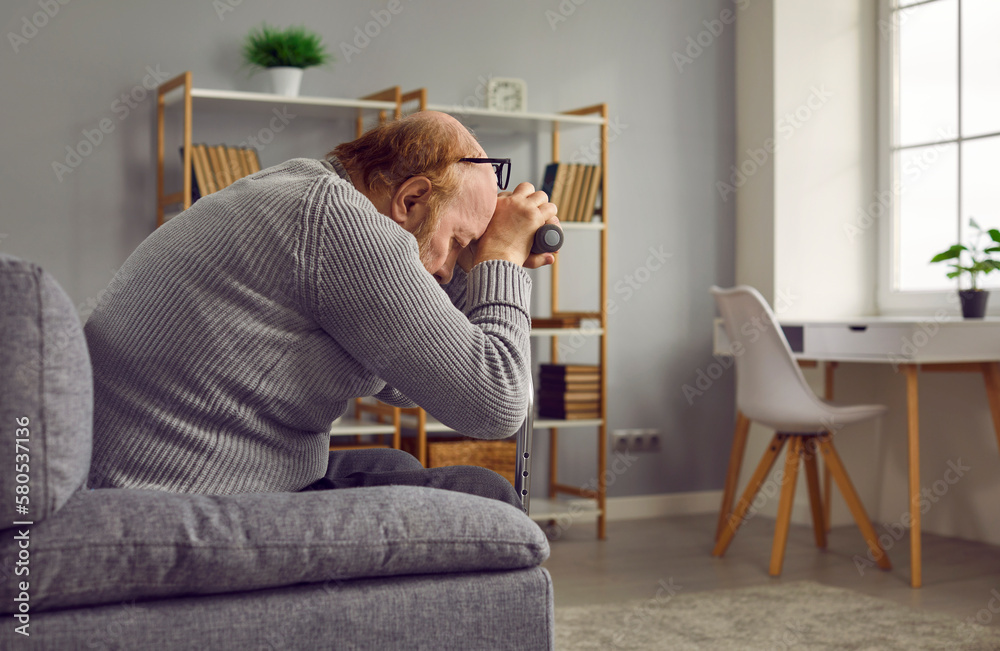 Sad retired senior man sitting on the sofa at home. Old man trying to ...
