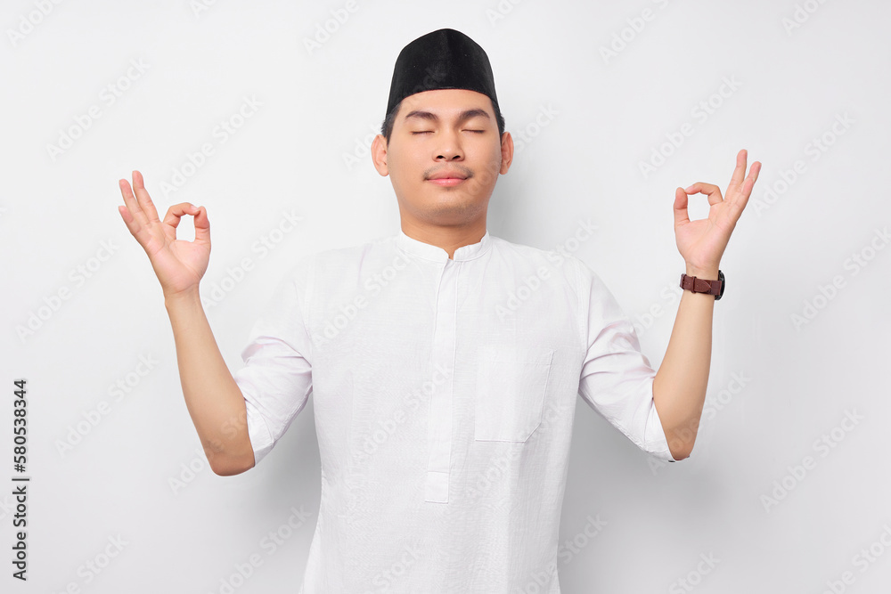 Handsome young Asian Muslim man standing with closed eyes ...