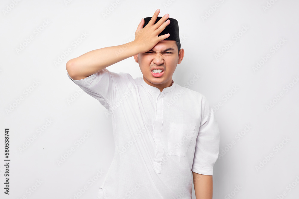 Upset young Asian Muslim man standing with his hand on his forehead and ...