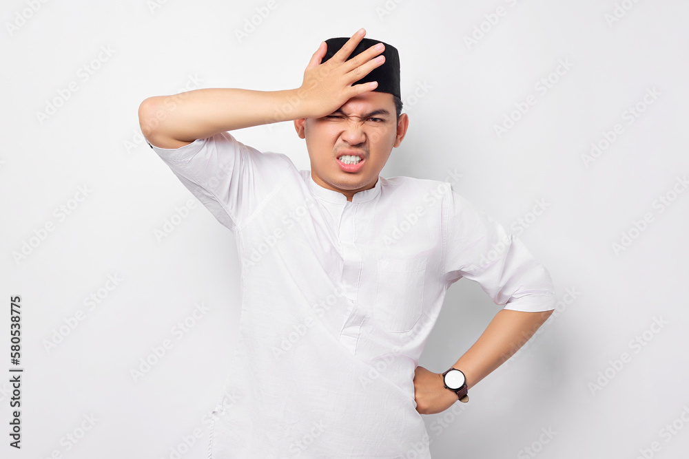 Upset young Asian Muslim man standing with his hand on his forehead and ...