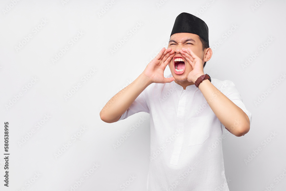 Excited young Asian Muslim man standing with open mouths raising hands ...